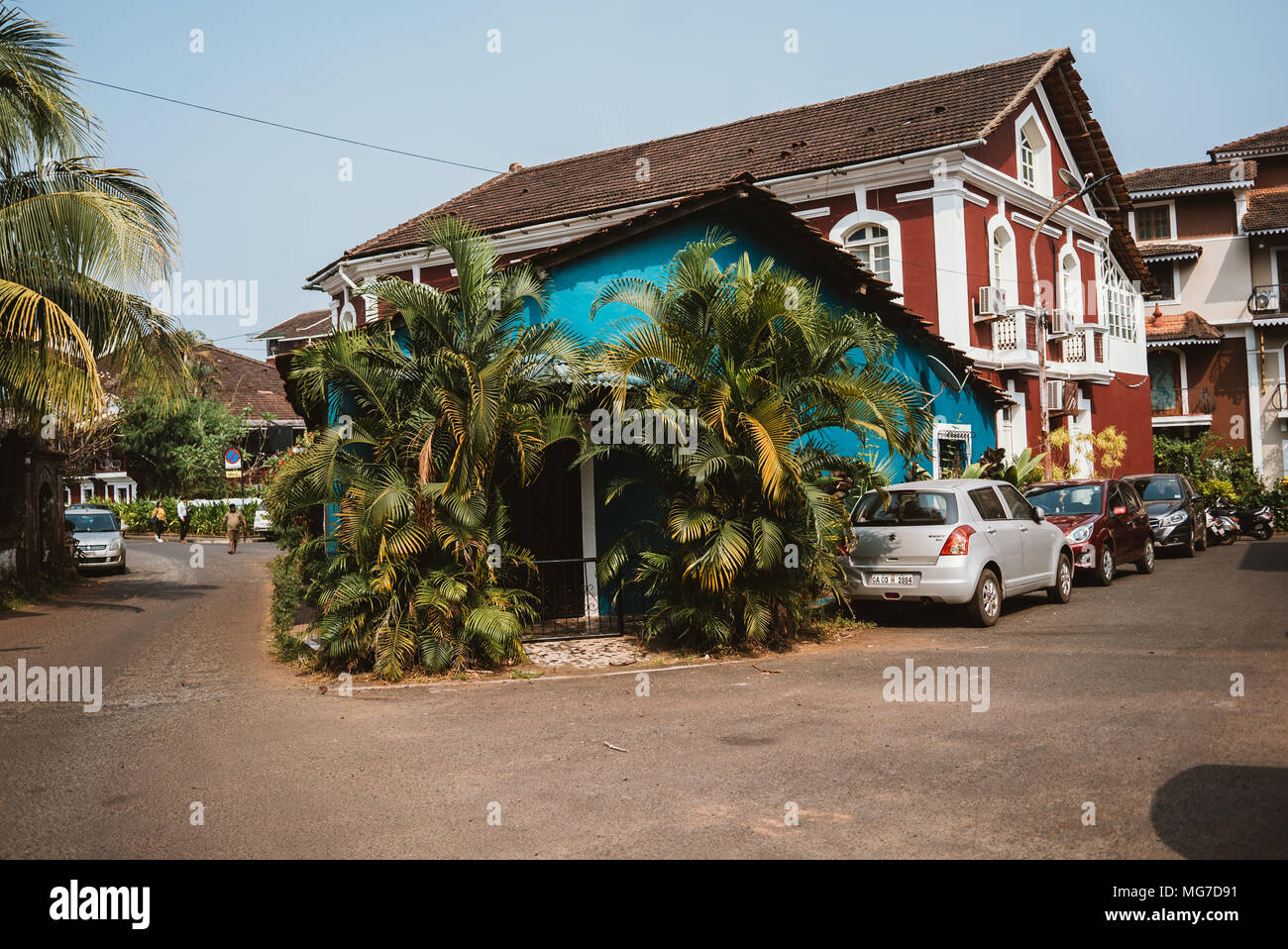 a bright blue teal house covered in plants on a corner in Goa, India ...