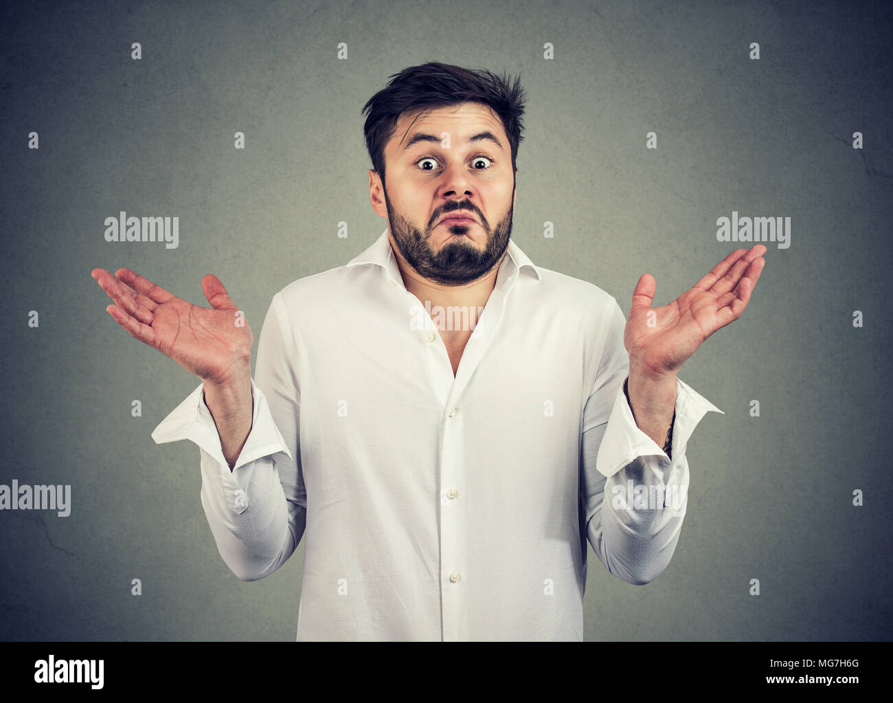 Young bearded man looking super puzzled and shrugging shoulders in ...