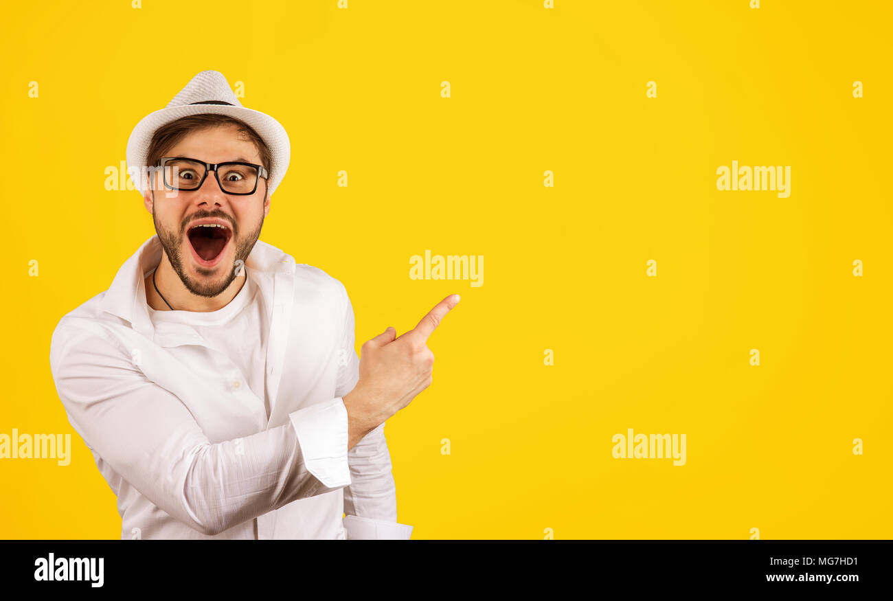 Cheerful hipster guy in white shirt and hat pointing up showing ...