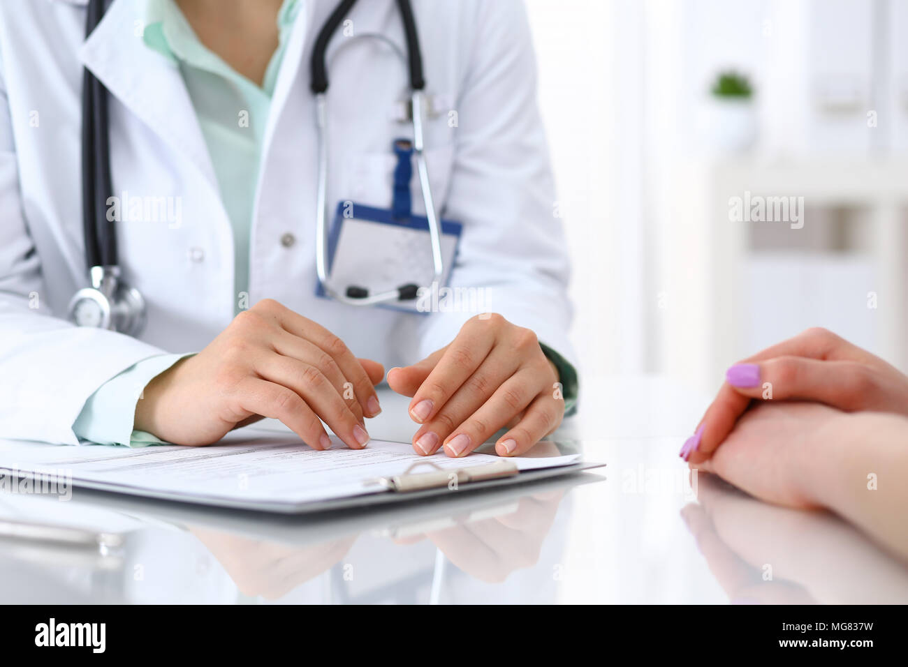 Doctor and patient talking while sitting at the desk in hospital office ...