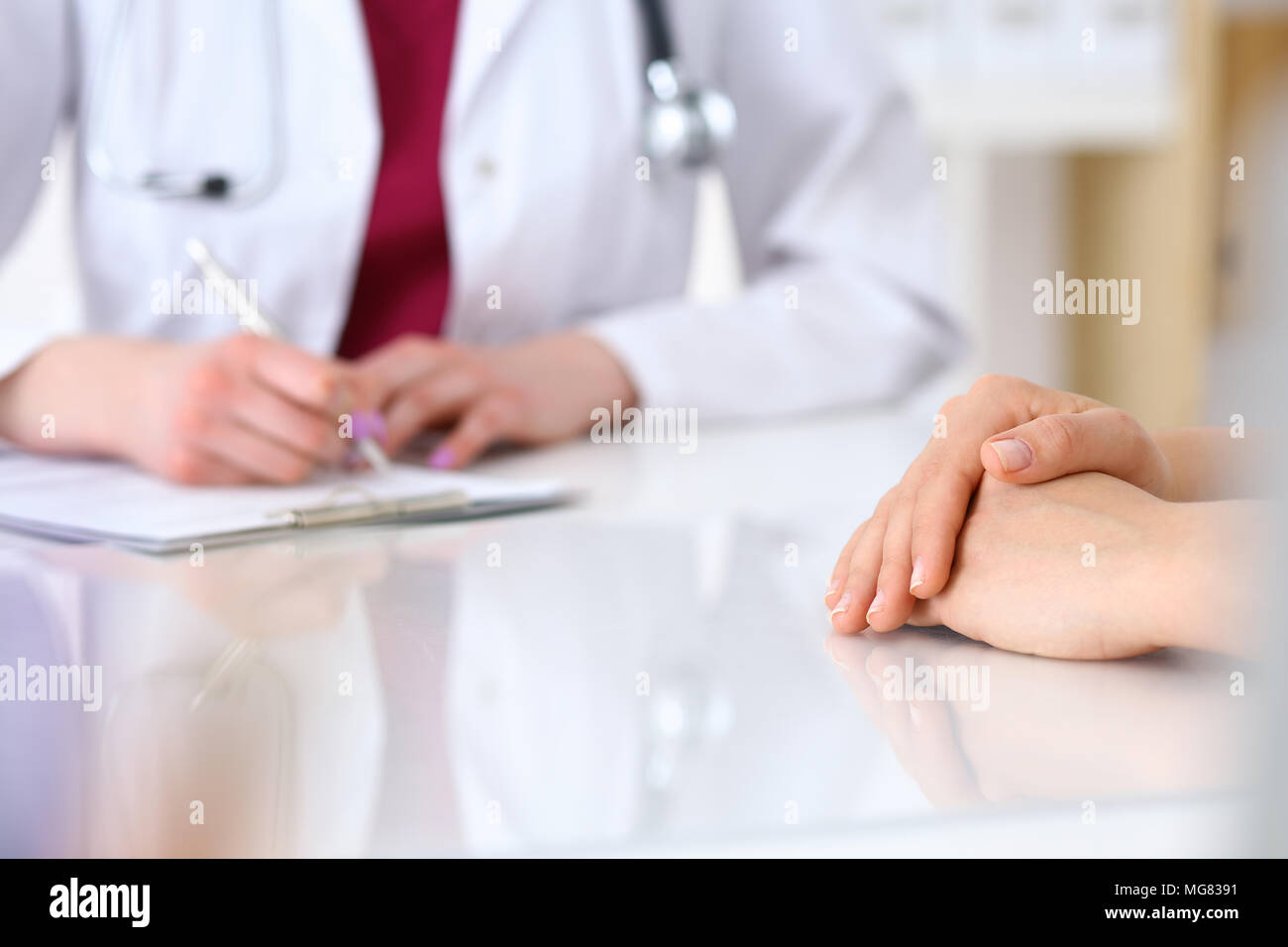 Female doctor filling up an application form while consulting patient ...