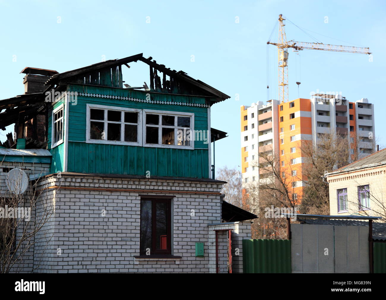 Old burnt house on the background of a new high-rise building under ...
