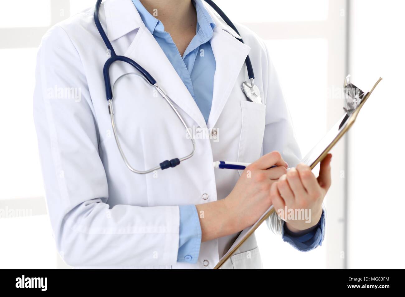 Female doctor filling up medical form on clipboard closeup. Physician ...