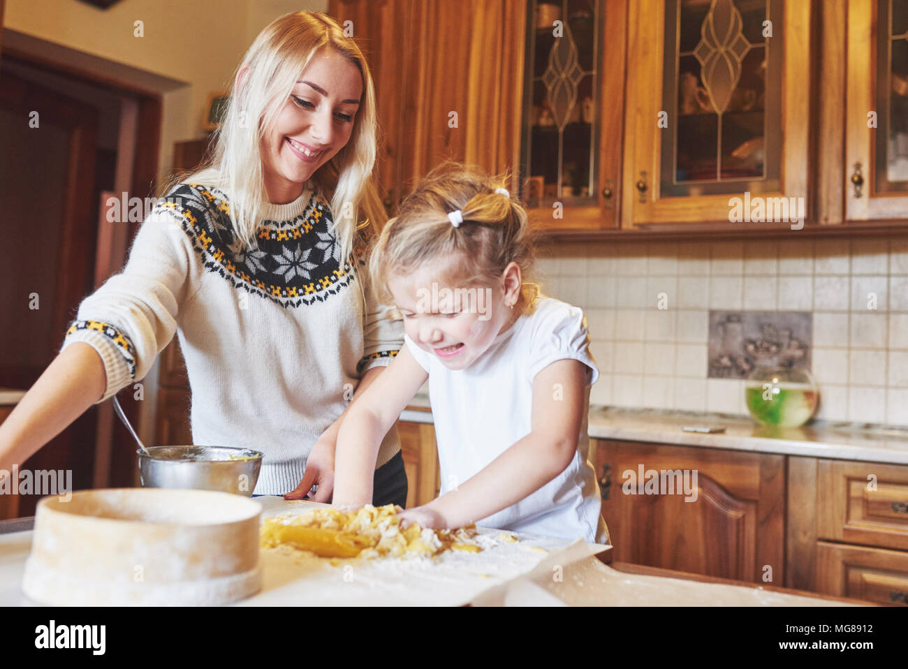 Happy smiling mom in the kitchen bakes cookies with her daughter Stock ...