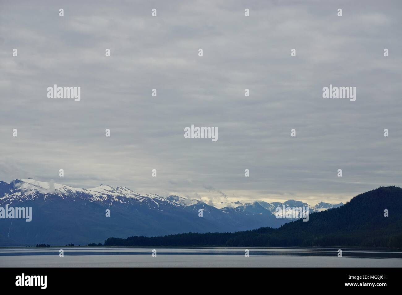 Endicott Arm, Alaska, USA: Snow-capped mountains under a cloudy sky in ...