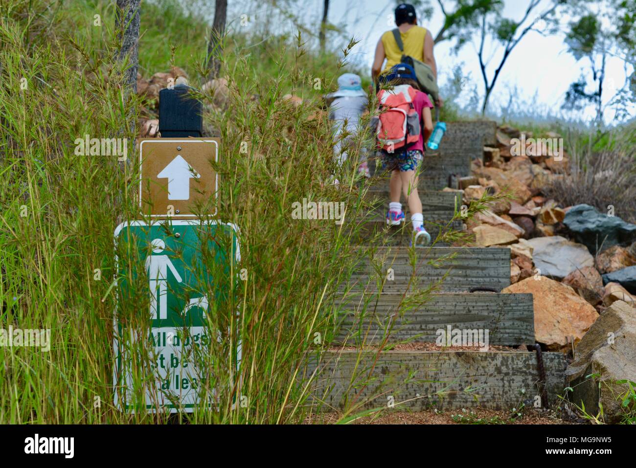 Mother and daughters walking past a All dogs must be kept on a leash ...