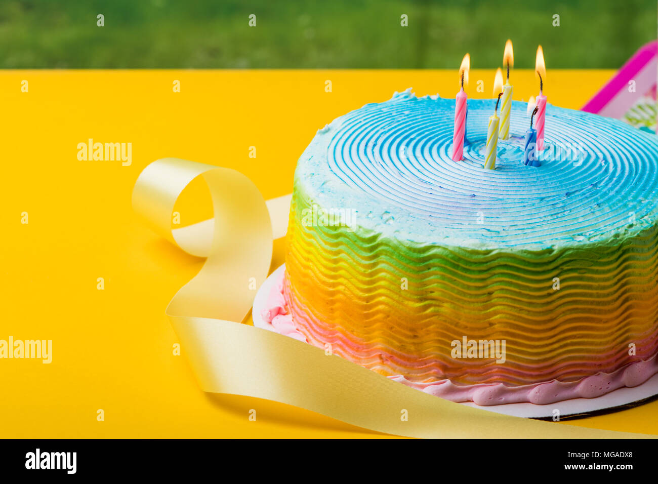 Frosted rainbow cake with candles and yellow ribbon Stock Photo - Alamy