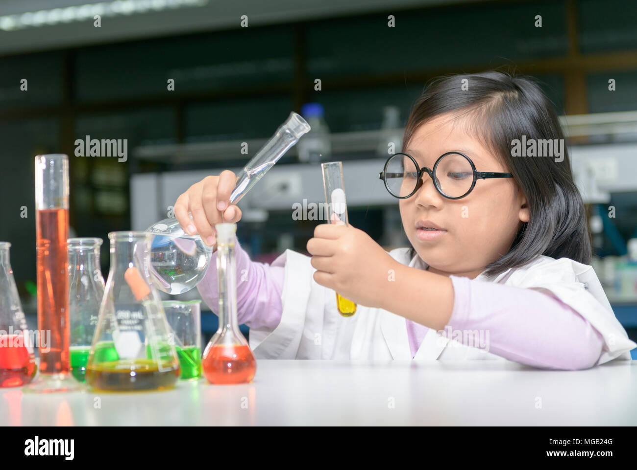 Happy scientist girl in lab coat making experiment with test tube in ...