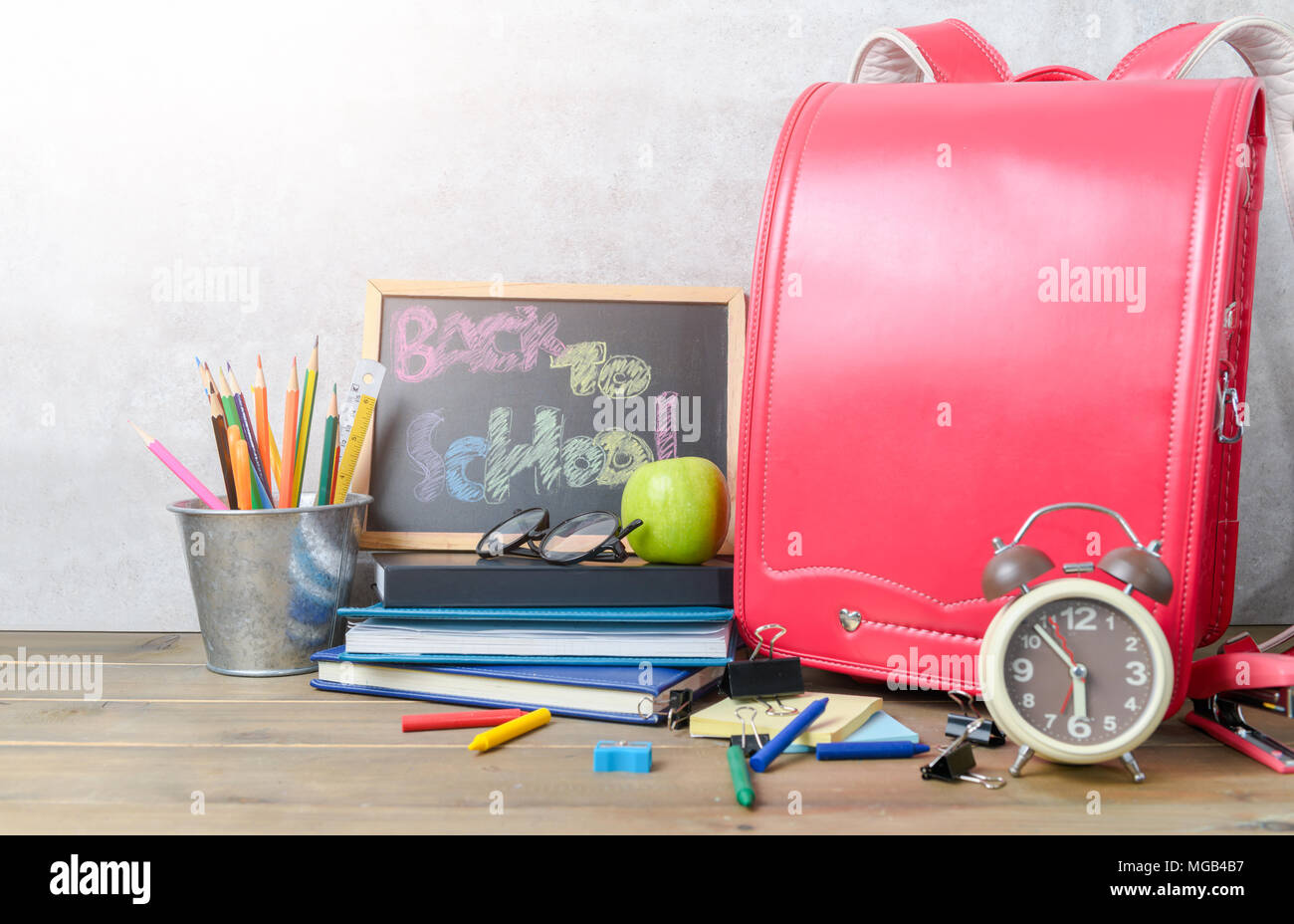back to school text on black chalk board with bag and school supplies ...