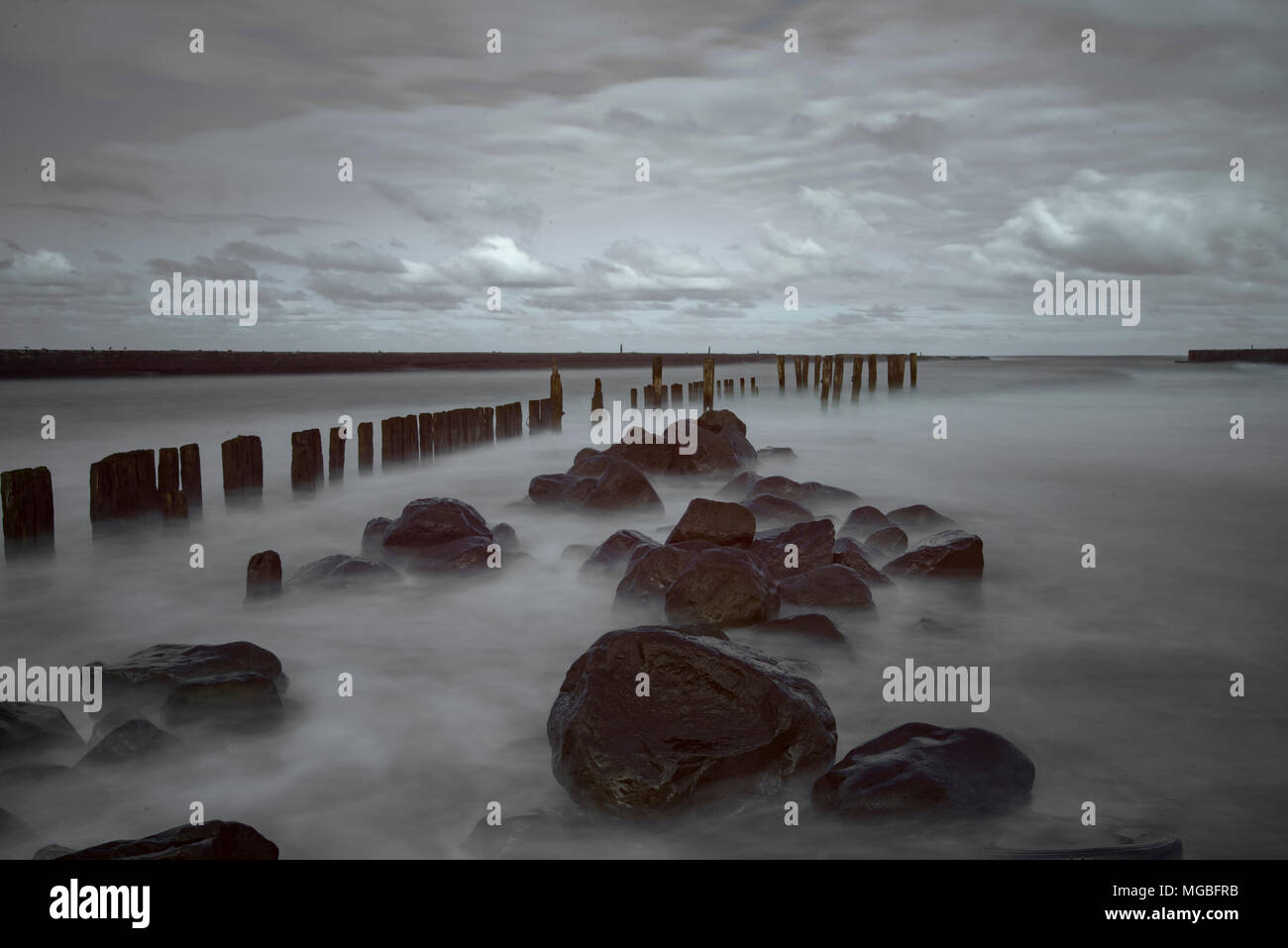 Long exposure sea wash over rocks and piles inside harbour Stock Photo ...