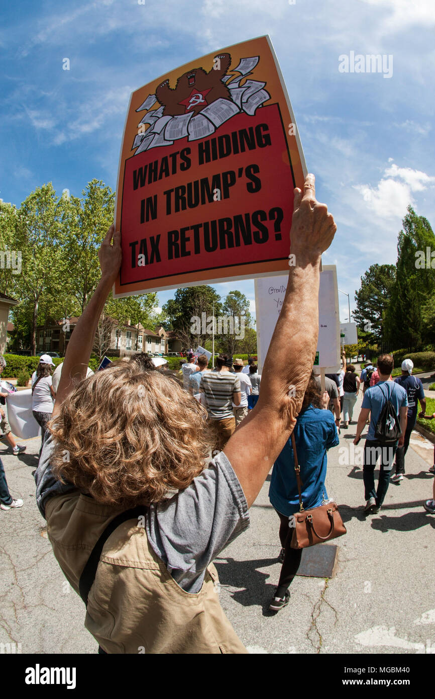A woman holds sign that says "What's hiding in Trump's tax returns?" as ...
