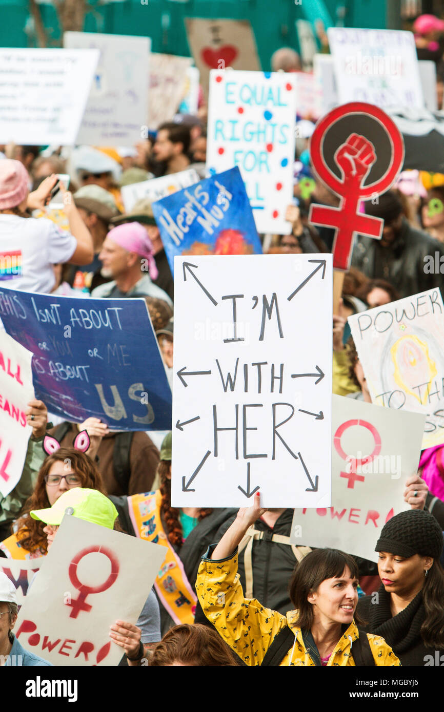 Woman holds up sign that says "I'm with her," as she is surrounded by ...