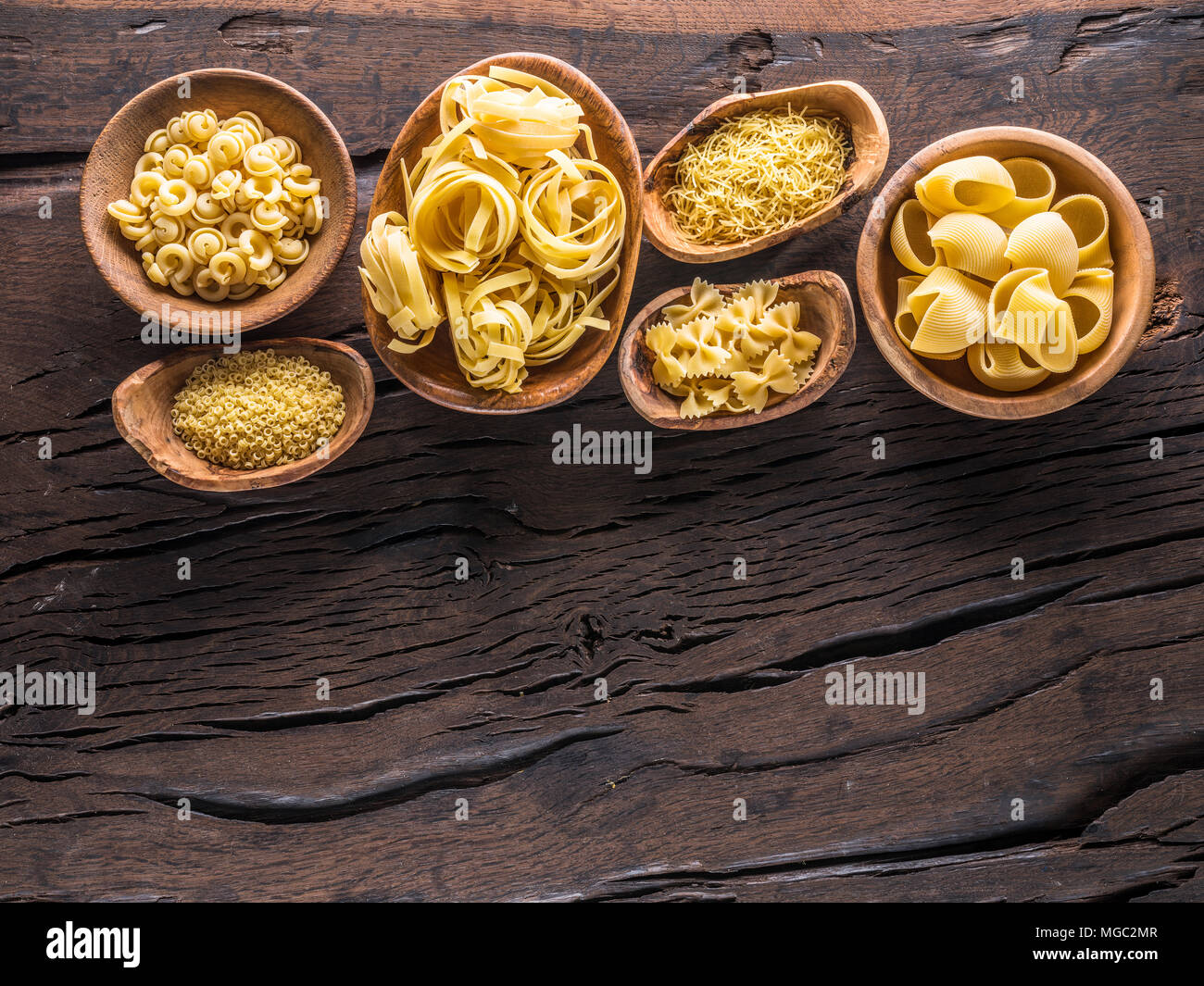 Different pasta types in wooden bowls on the table. Top view Stock ...