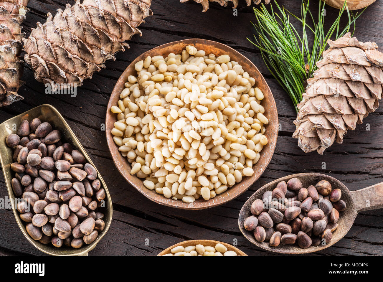 Pine nuts in the bowl and pine nut cones on the wooden table. Organic ...