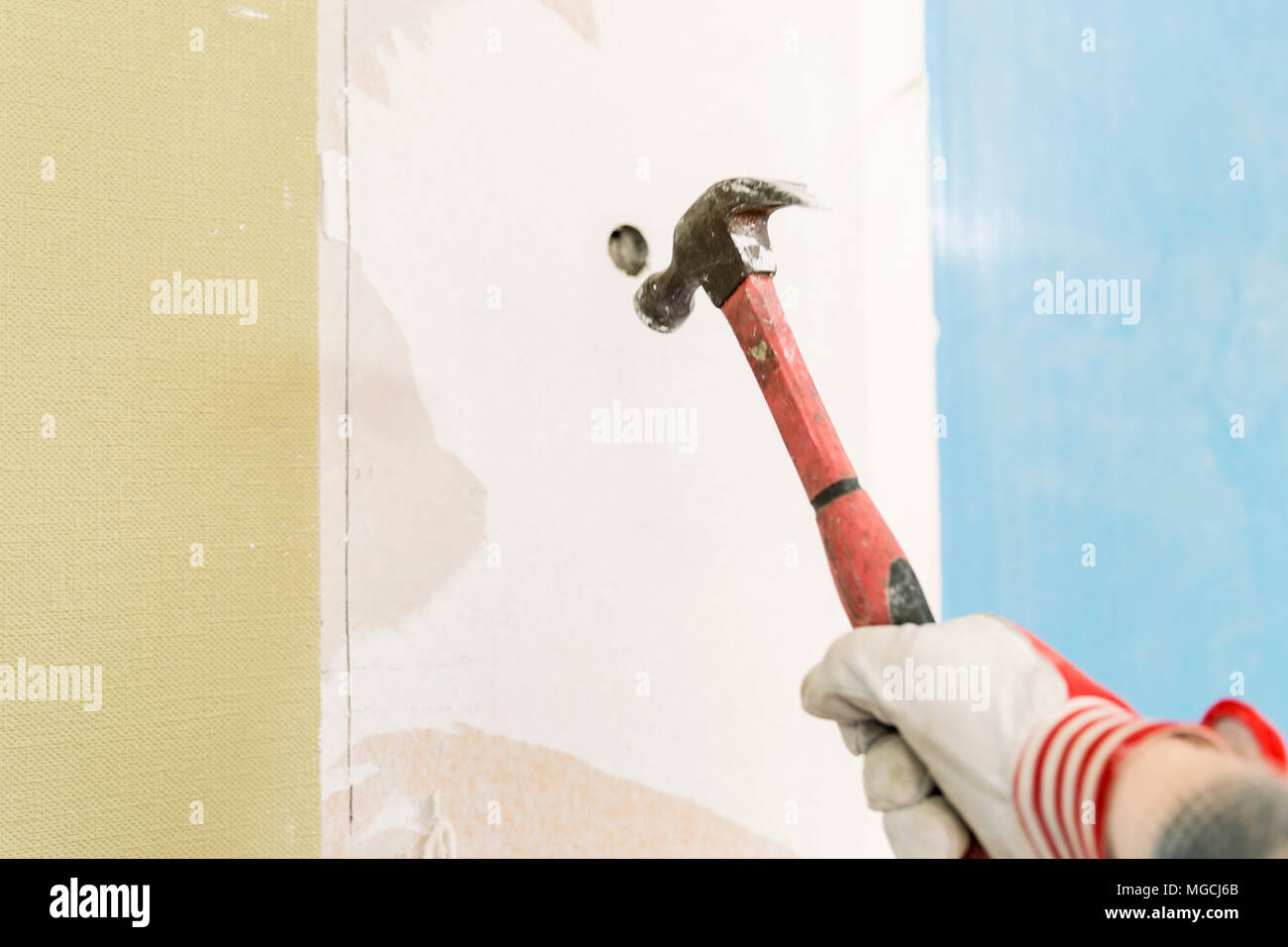 Builder hitting a wall with a hammer. Home renovation concept. Break ...