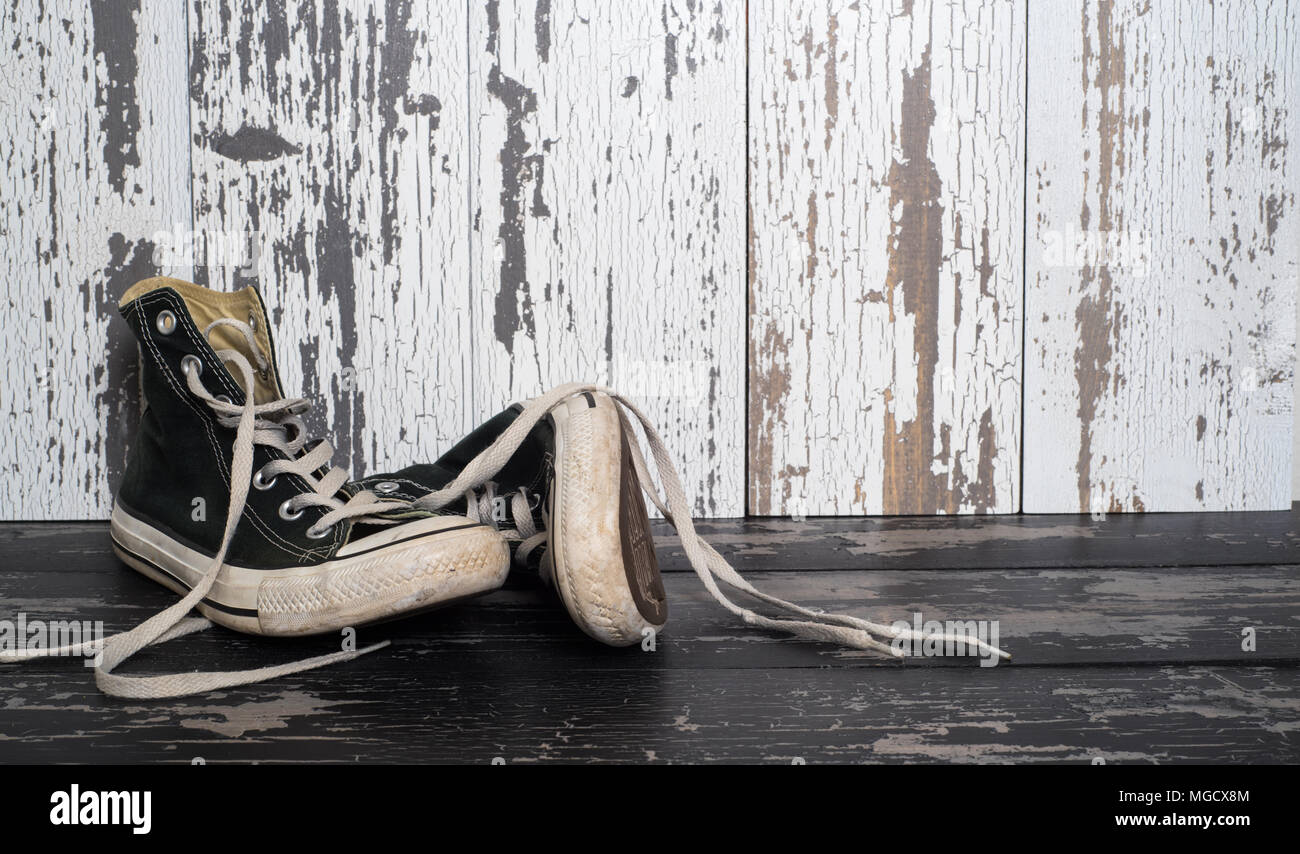 Old, dirty, retro, classic, canvas tennis shoes on a wood plank ...