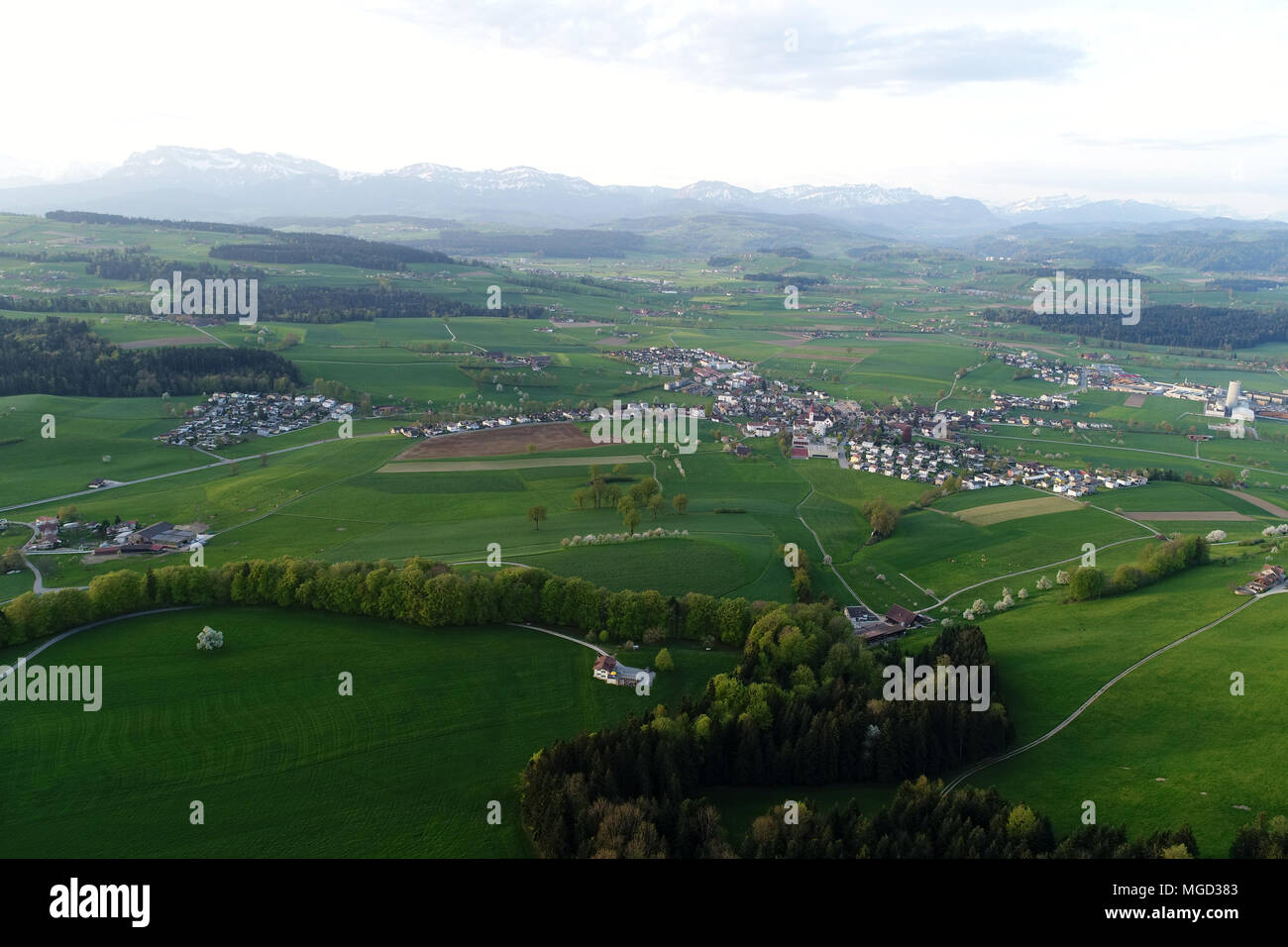 Swiss lowland with villages, farms and the Alps in the background on a ...