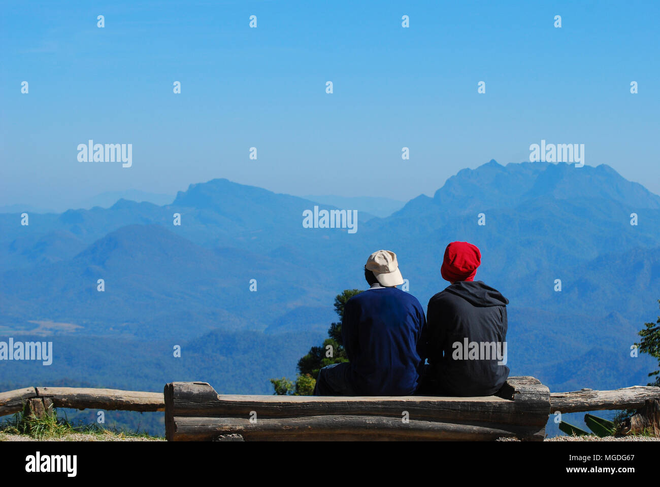 Two men sitting on bench looking the nature viewpoint on mountain top ...