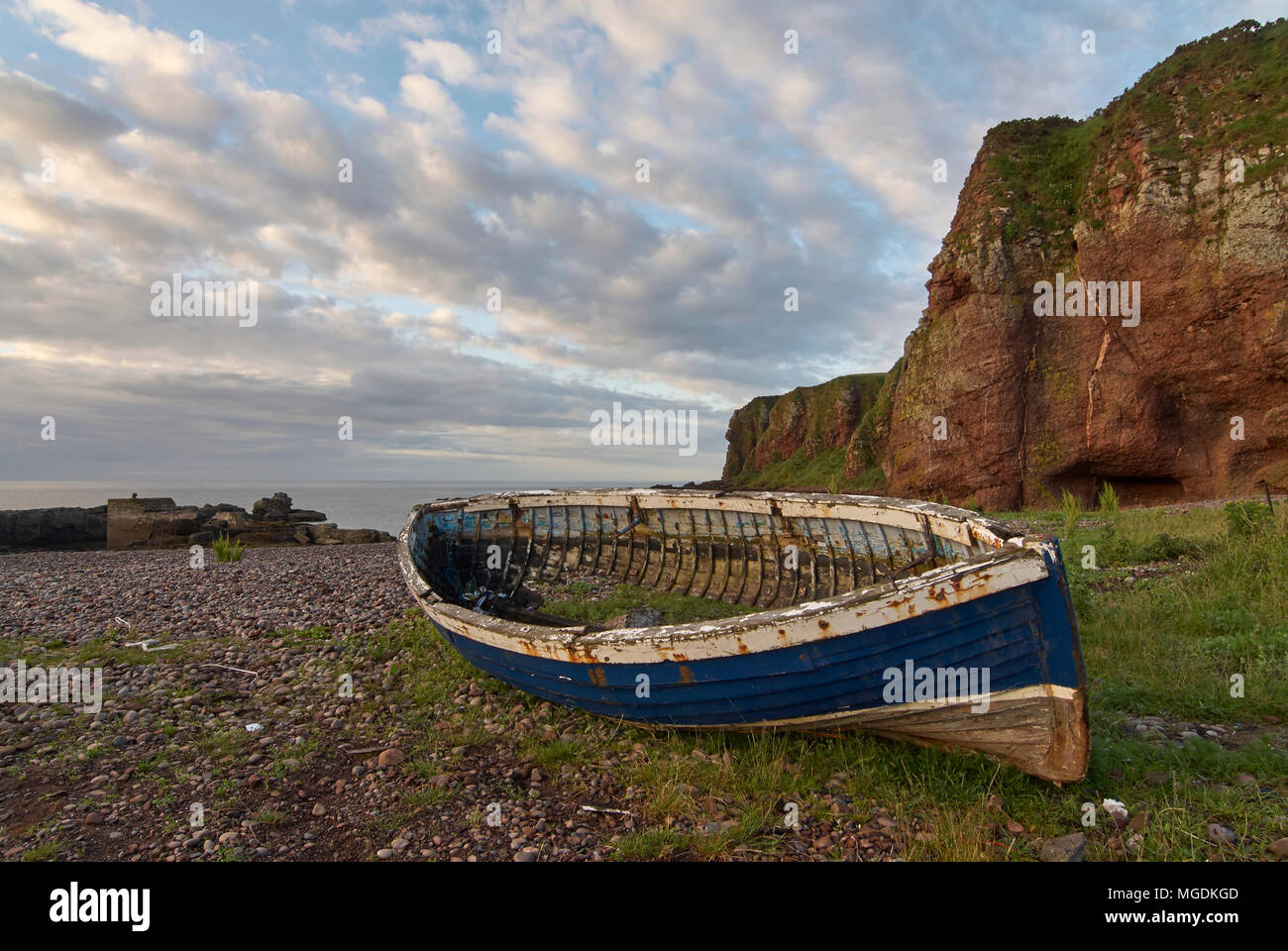 An Old Wooden Scottish Fishing Boat, long abandoned, lies on the Pebble ...