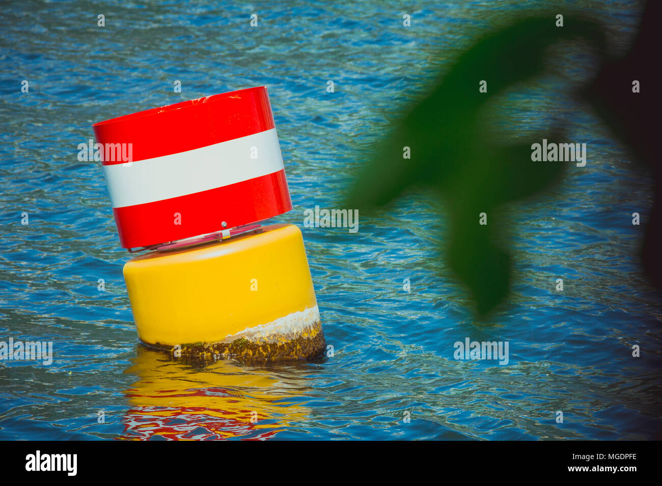 Yellow red and white steel navigational floating buoy in the blue sea ...