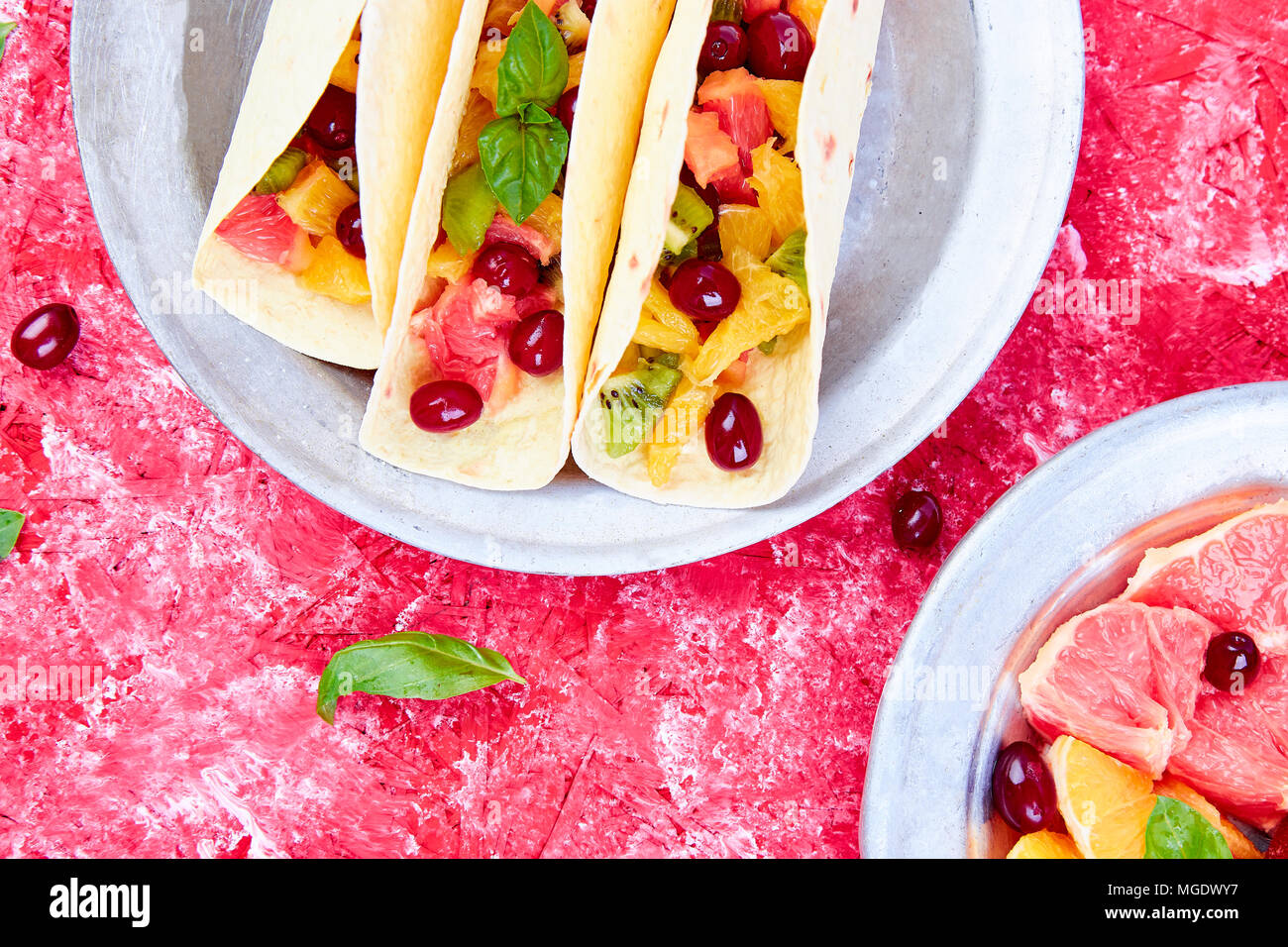 Fruit tacos with orange, kiwi, grapefruit red background and berry ...