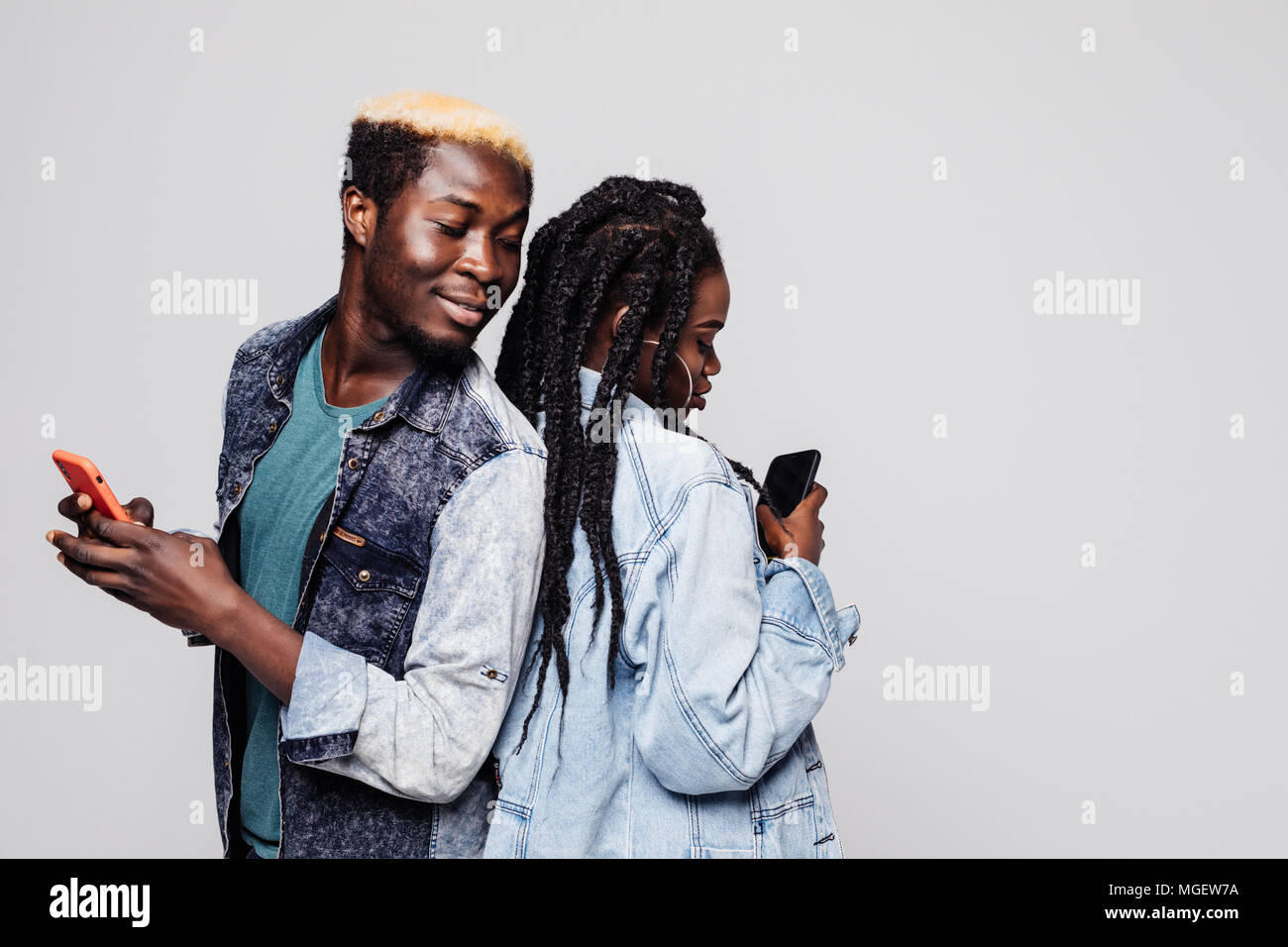 Side portrait of african couple standing back to back holding mobile ...