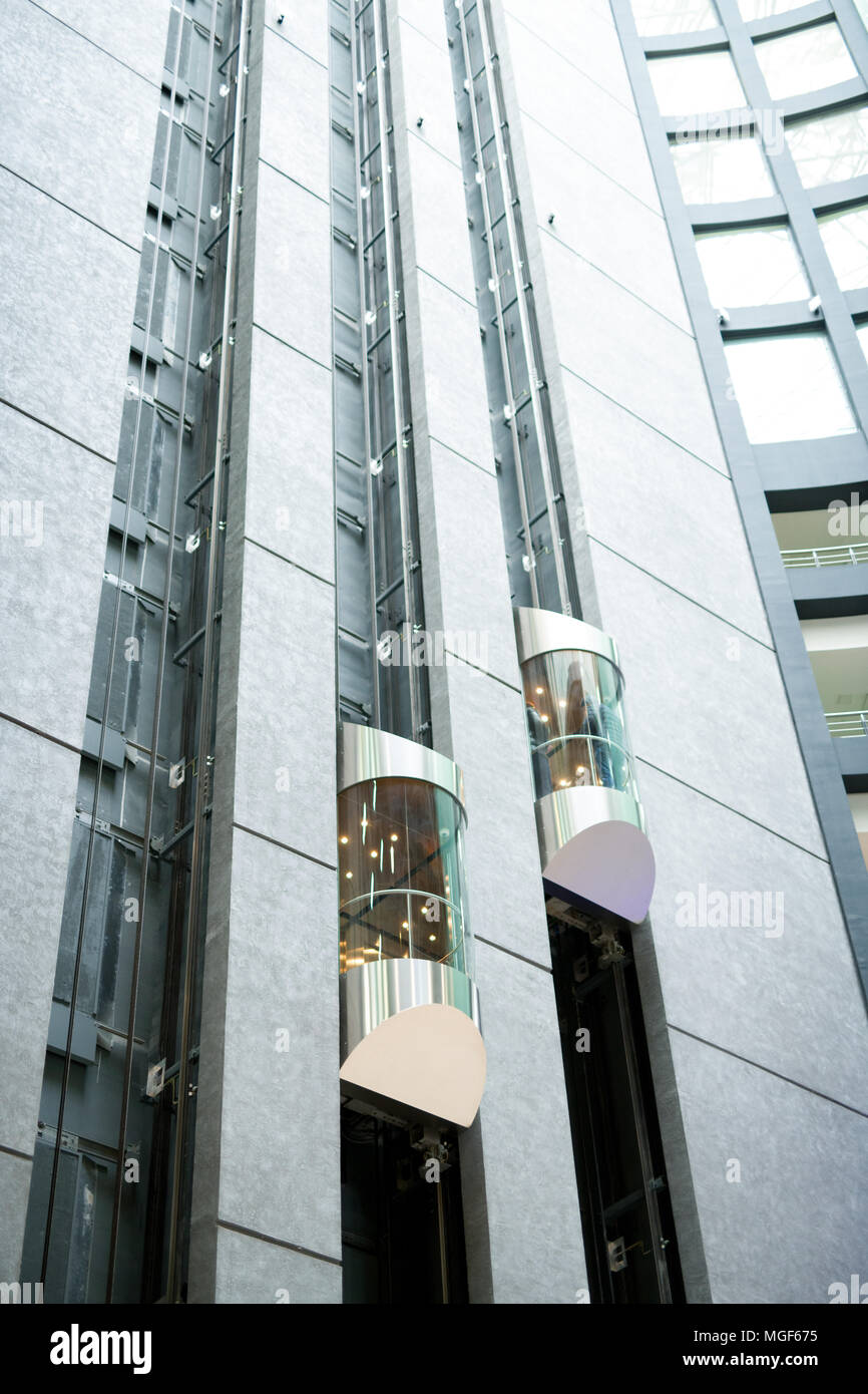 Tall modern office hall with moving glassy elevators, urban business ...