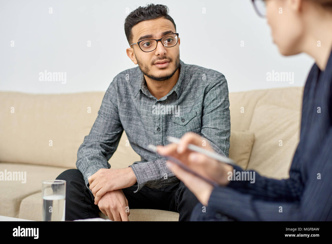 Handsome young man suffering from depression sitting on cozy sofa and ...