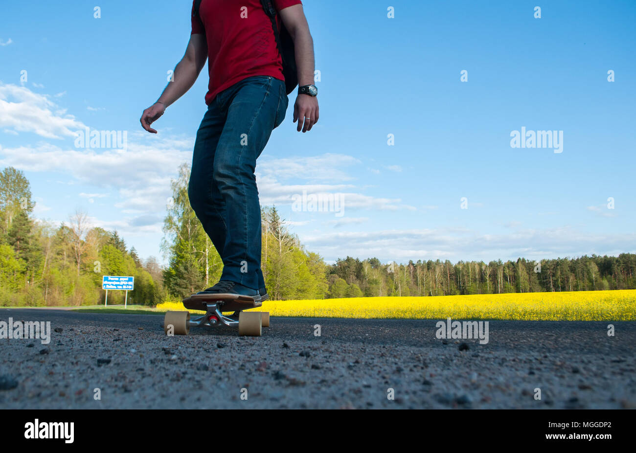 A man rides a longboard in the background of the rural landscape ...