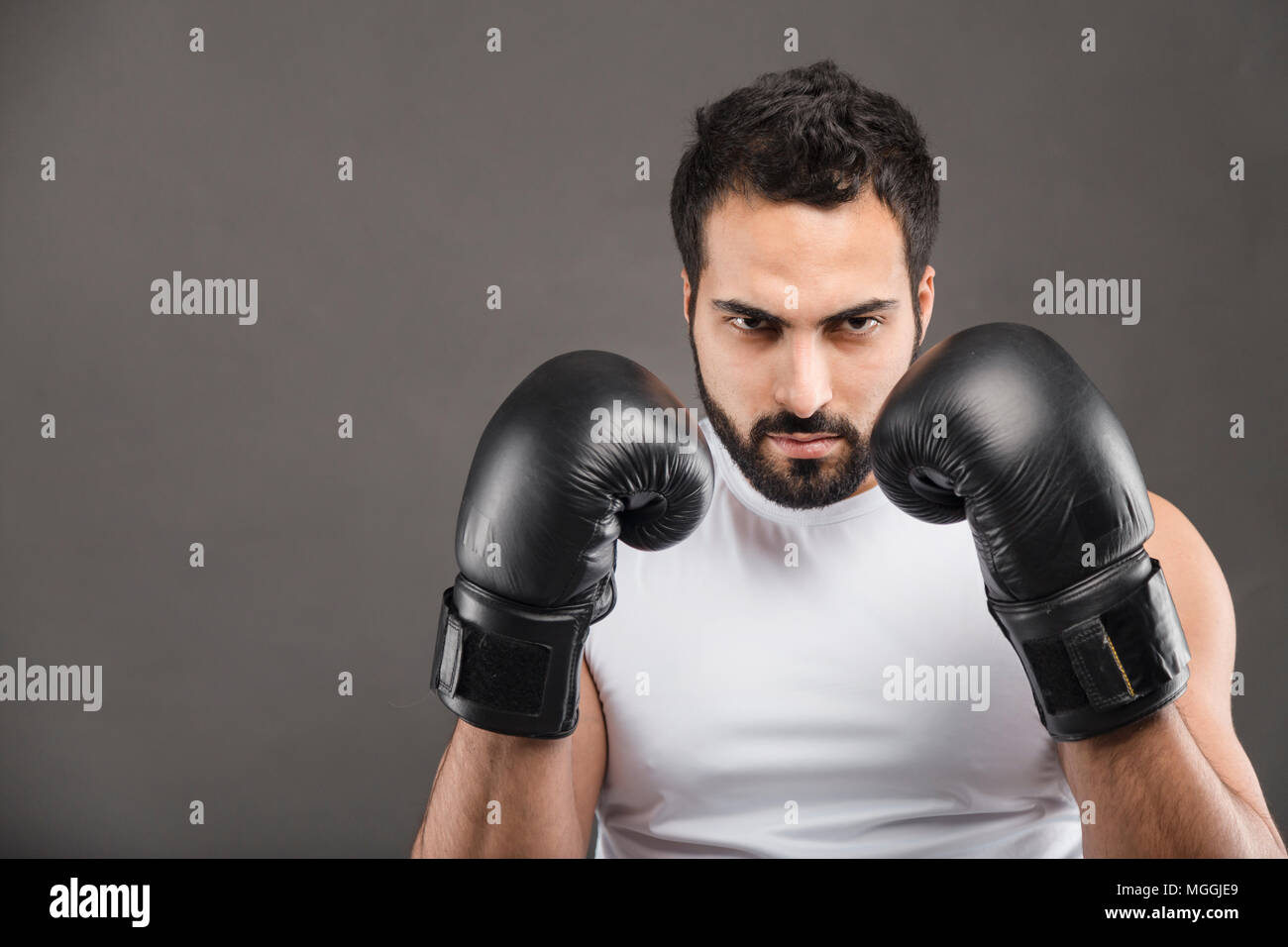 Handsome bearded man in boxing gloves and white shirt on isolated grey ...