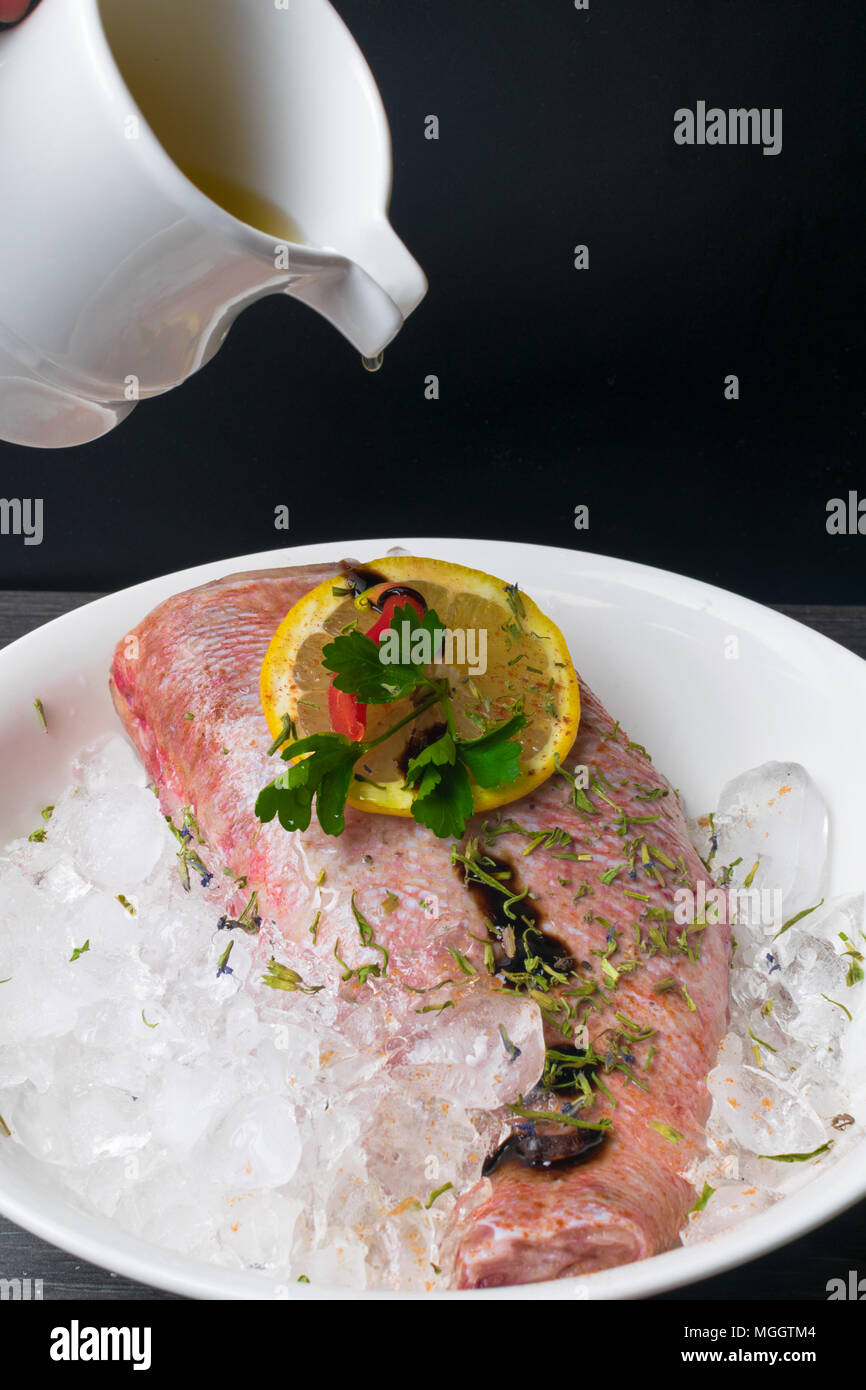 Whole raw organic fish sea perch on ice cubes with lemon, sy sauce ...