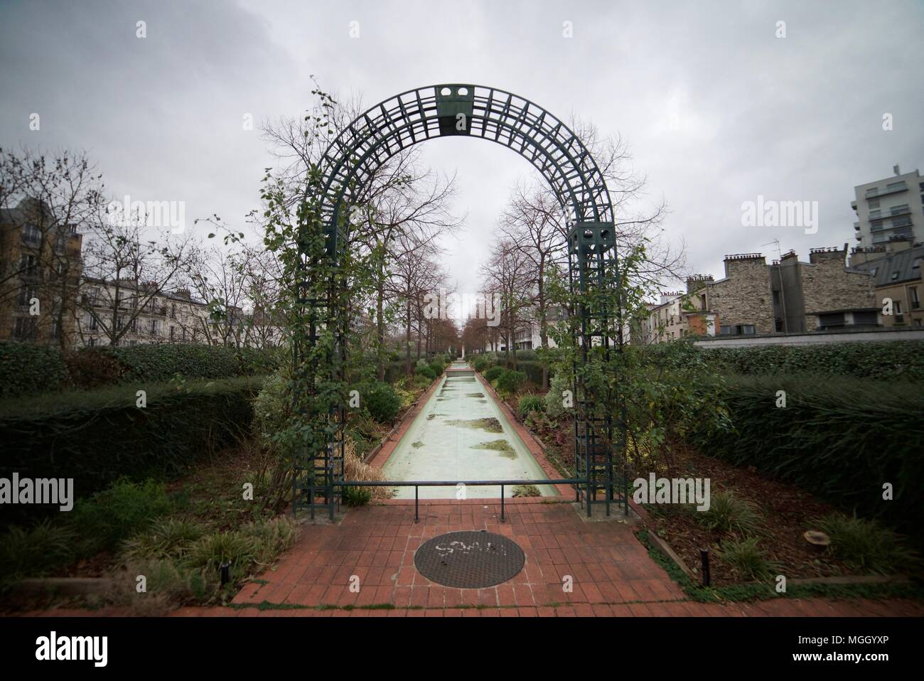 An archway and path through a garden of flowers and plants growing ...