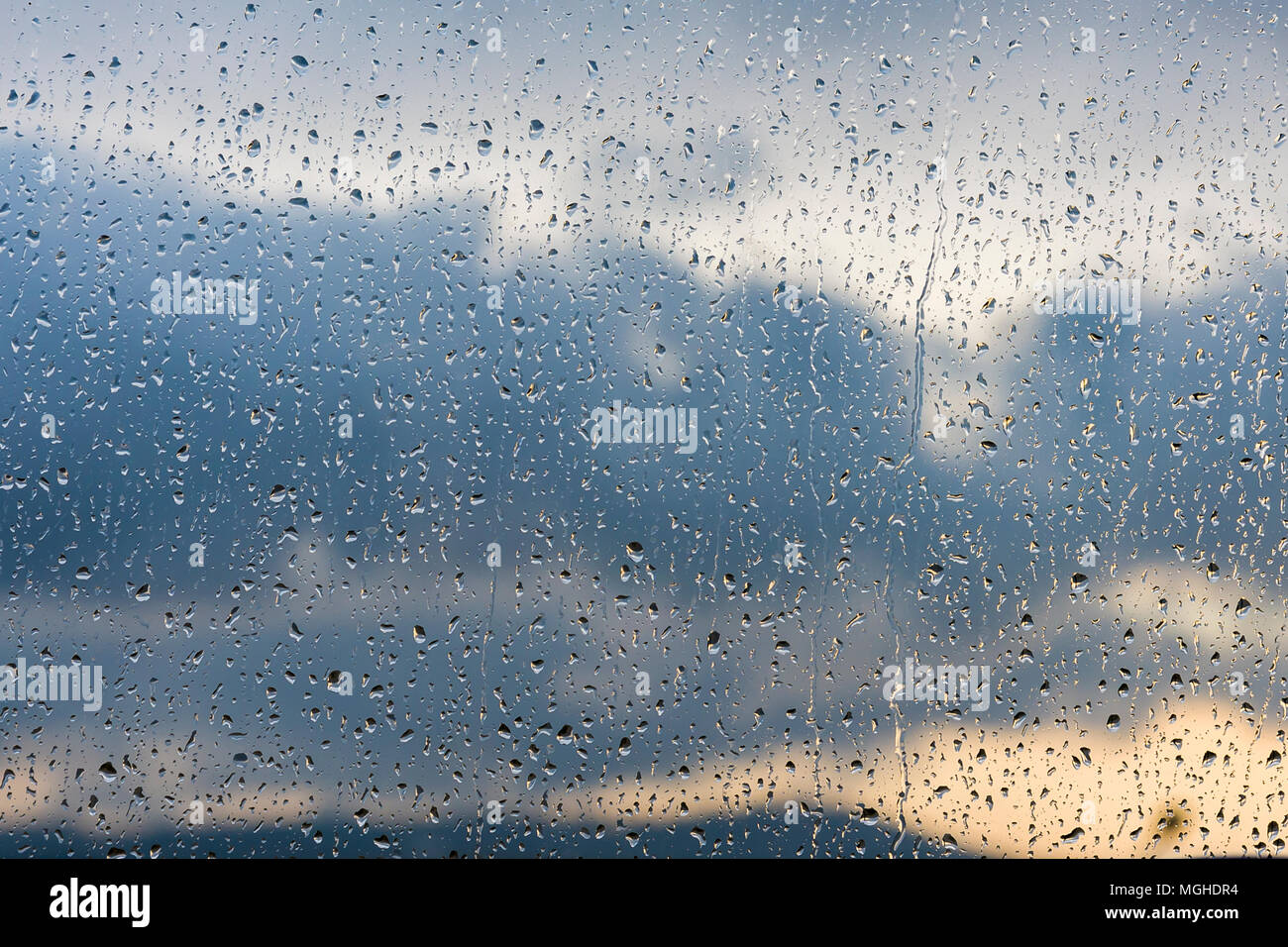 The sky with clouds and sun on background. drop on the glass window ...