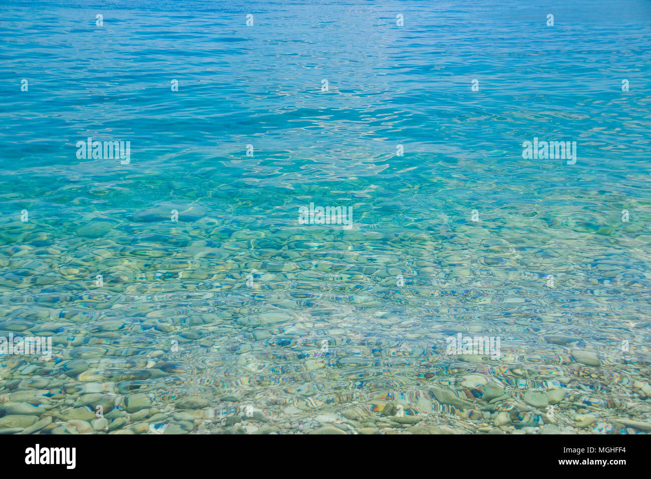 Transparent shallow water with rocky bottom, fading away to deeper area ...