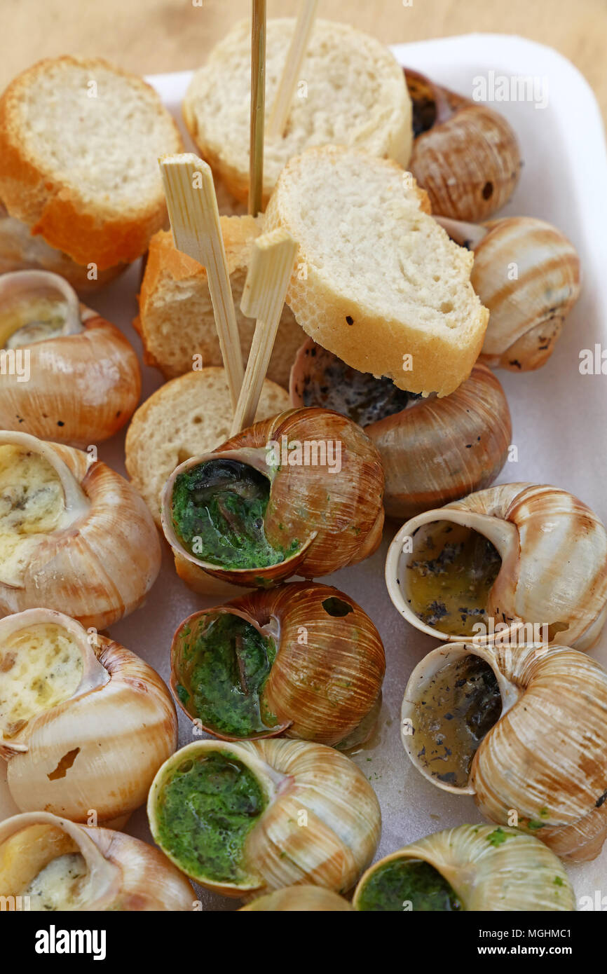 Close up street fast food take away portion of cooked escargot snails ...