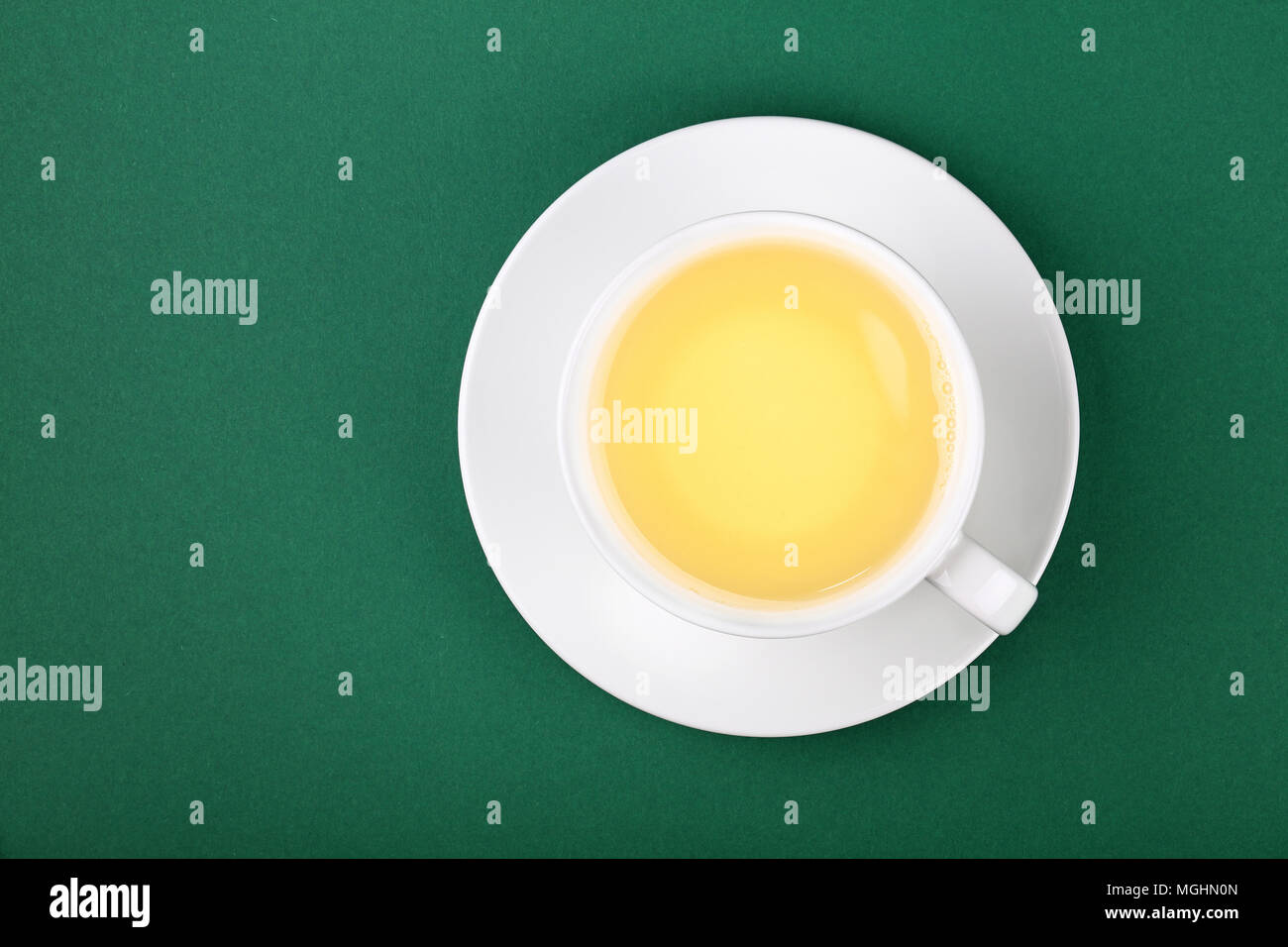 Close up one full white cup of green oolong tea on saucer on green ...