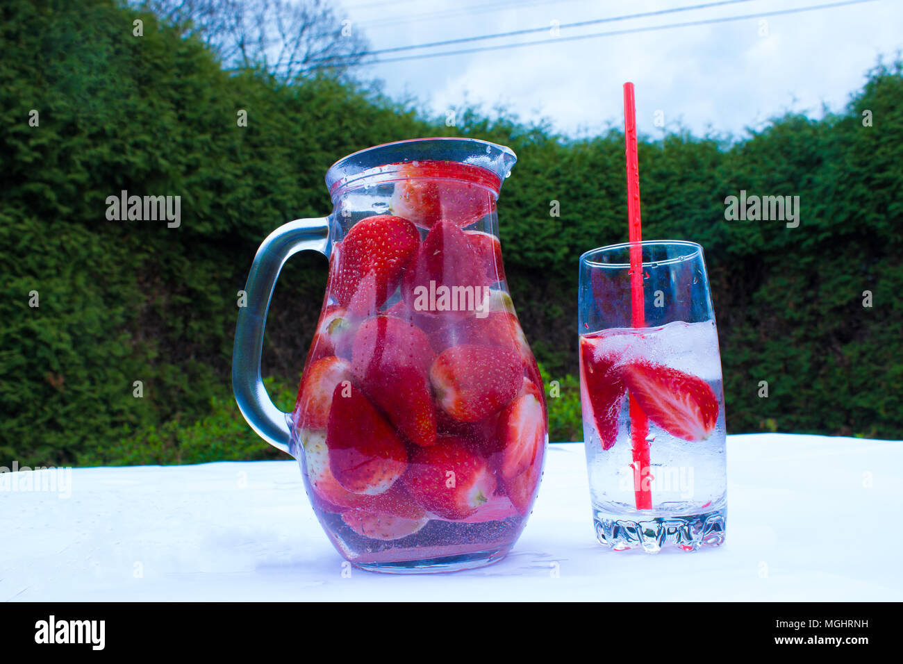 Strawberry drink in a pitcher and a glass of drink with ice cubes and a ...