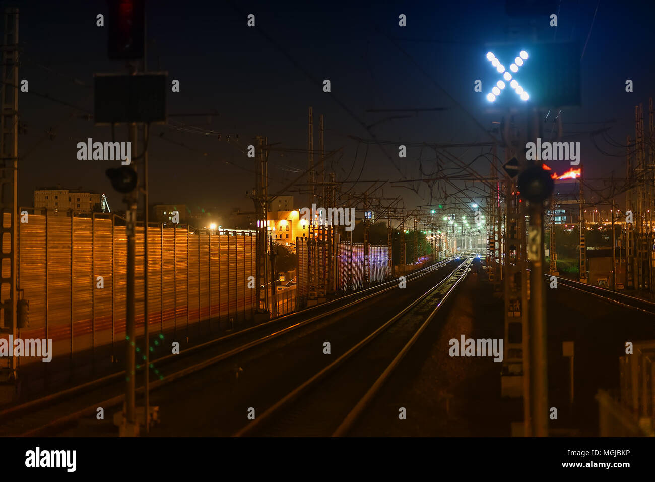 Railroad night scene with blue traffic light and railway station tracks ...