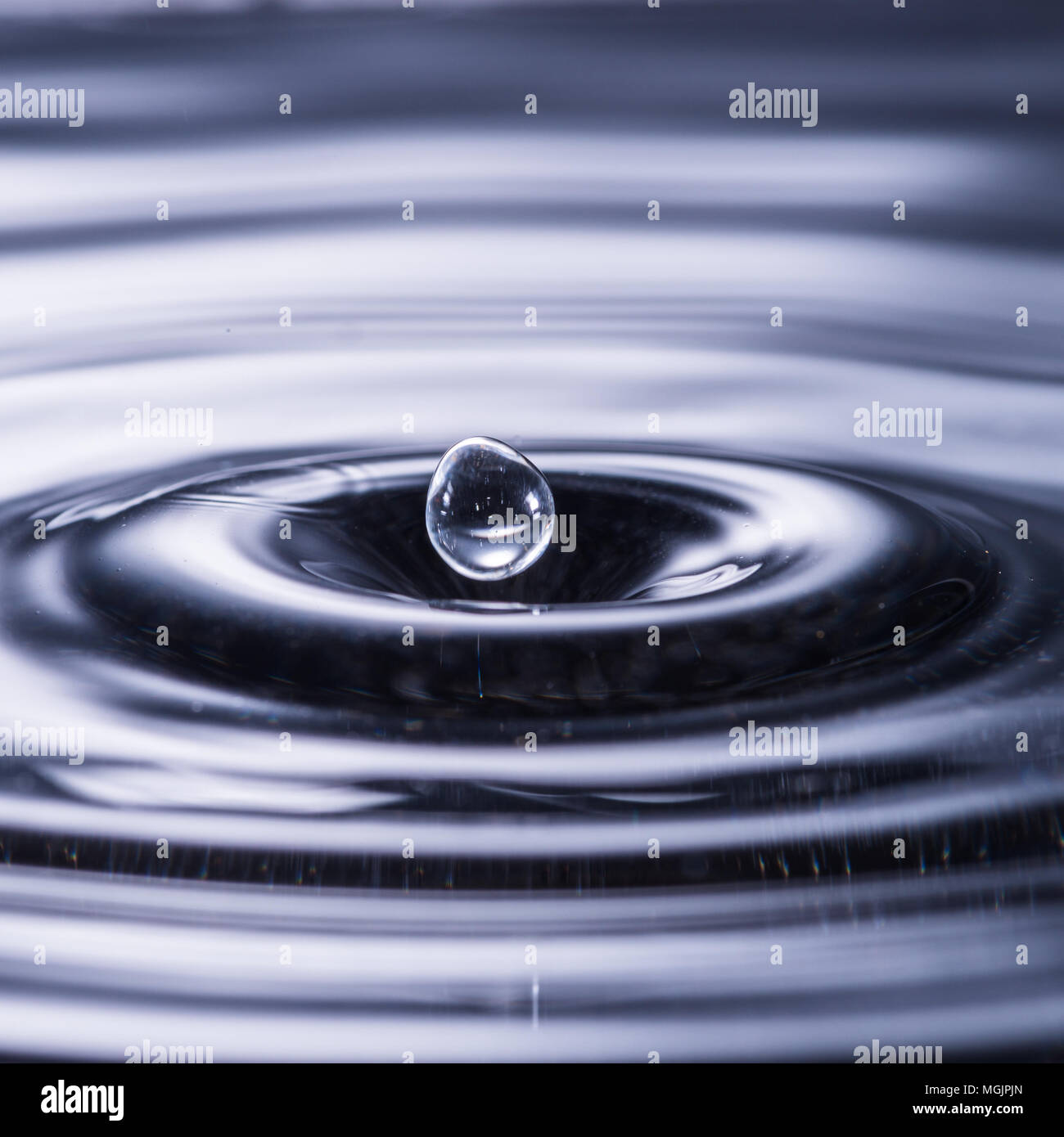 A water drop falling towards a pool of water Stock Photo - Alamy