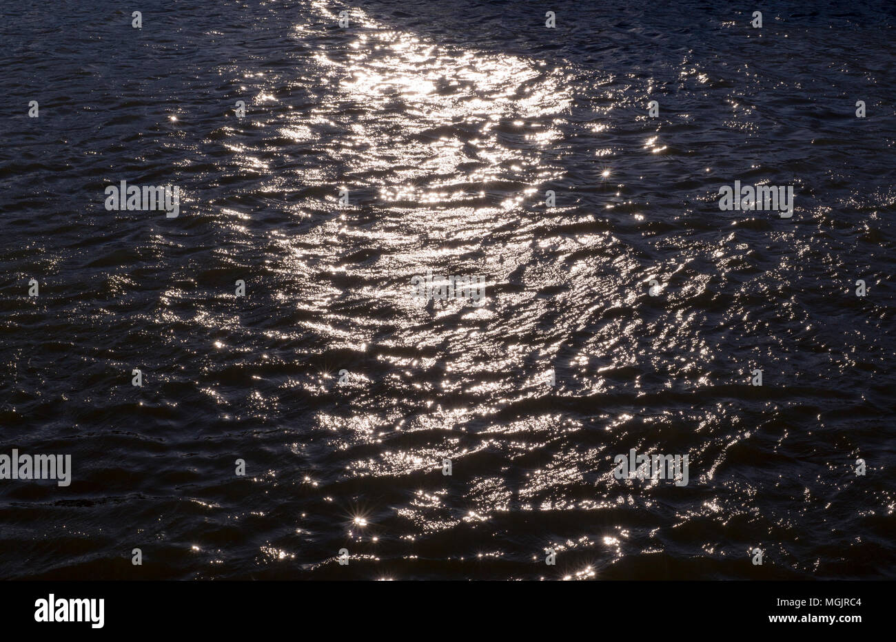 reflections of evening sun on rippled water in the river. background ...