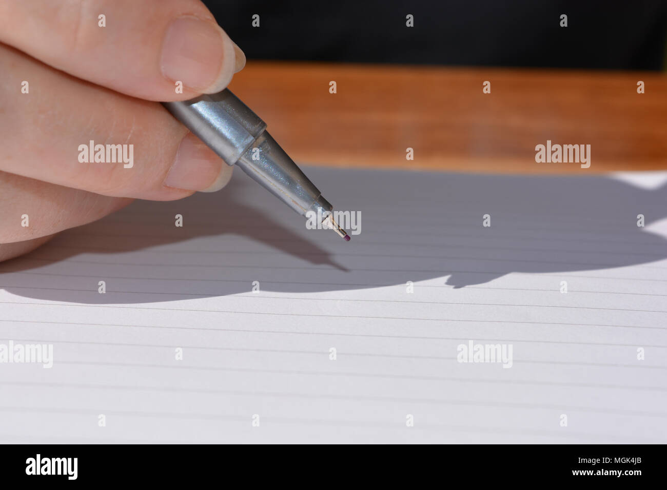 Woman with pen in hand, poised to write in a spiral bound notebook ...
