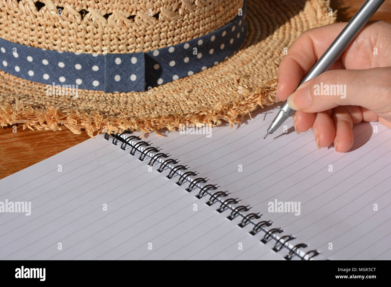 Woman with pen in hand, poised to write in a spiral bound notebook ...