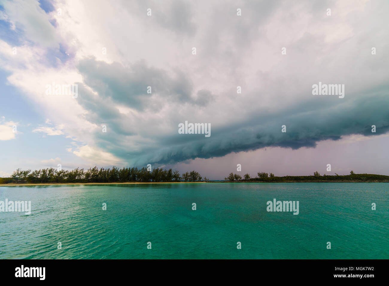 Tropical storm clouds approach over an isolated island with calm water ...
