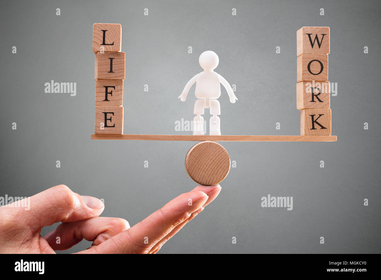A Person's Hand With Human Figure Standing Between Work And Life Wooden ...
