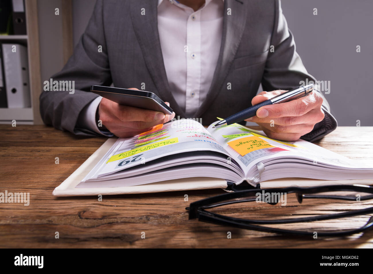 Businessperson's Hand Writing Schedule In Diary With Pen On Wooden Desk ...