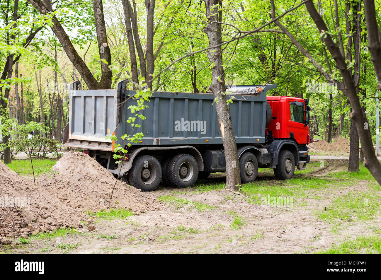 Big tipper truck near soil heap. Reconstruction of city park with heavy ...