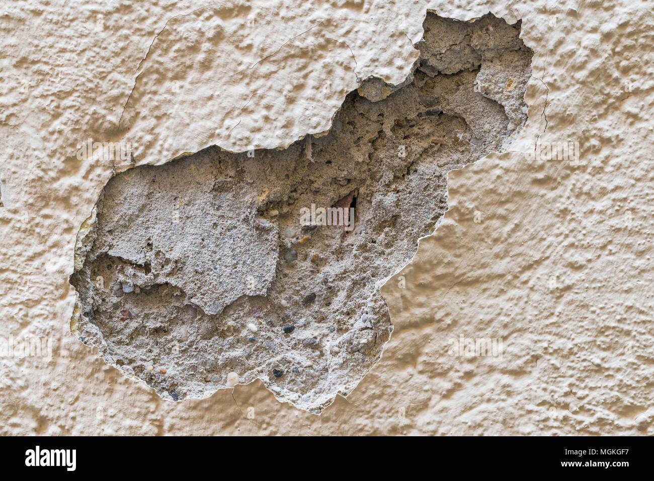 A damaged house wall and flaked exterior plaster with a large hole ...