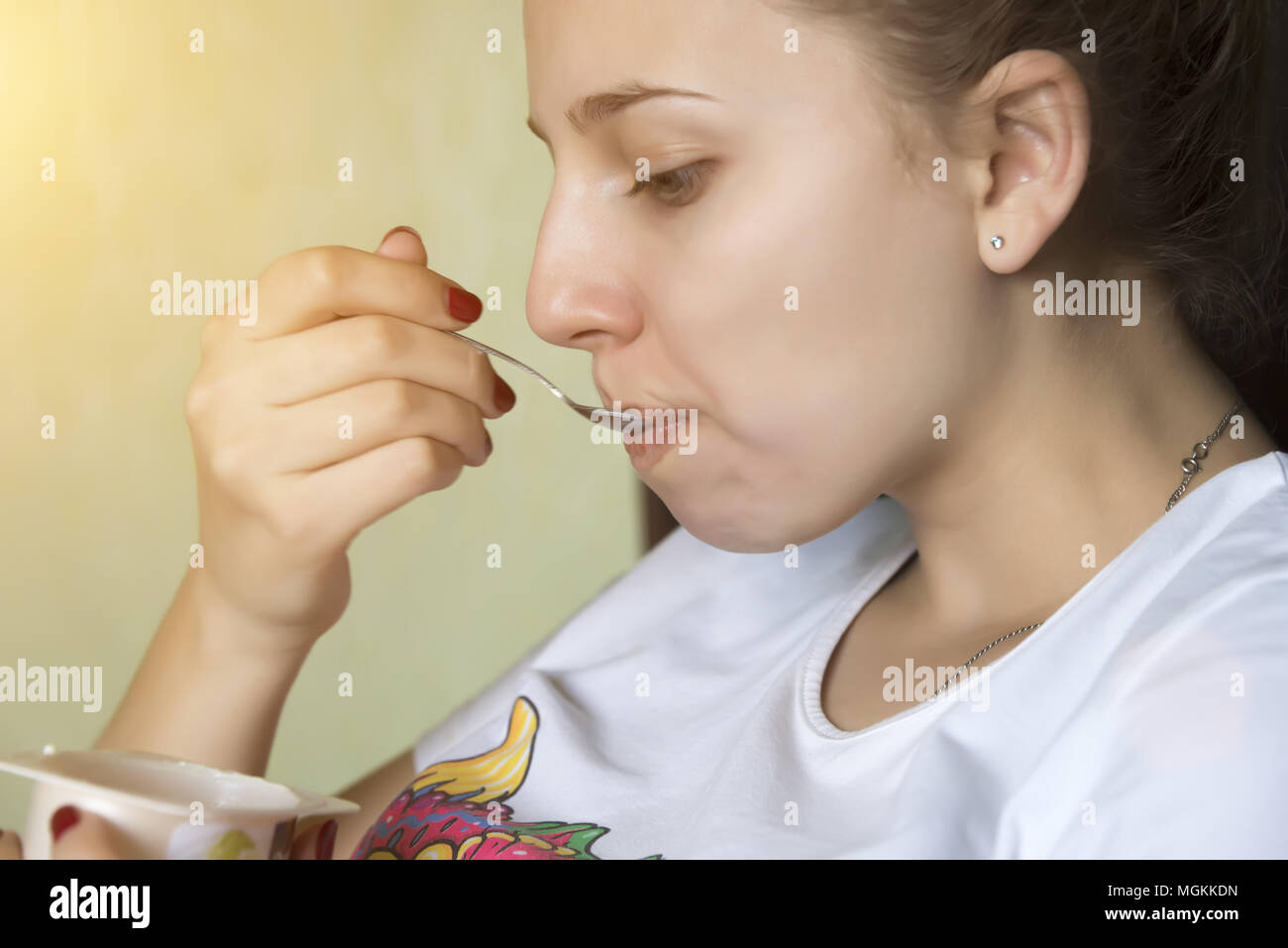 pretty girl eating a yogurt spoon out of a jar Stock Photo - Alamy