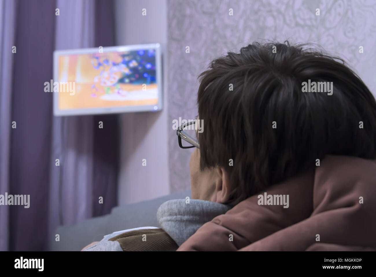 girl with glasses watching TV, lying on the couch, rear view Stock ...