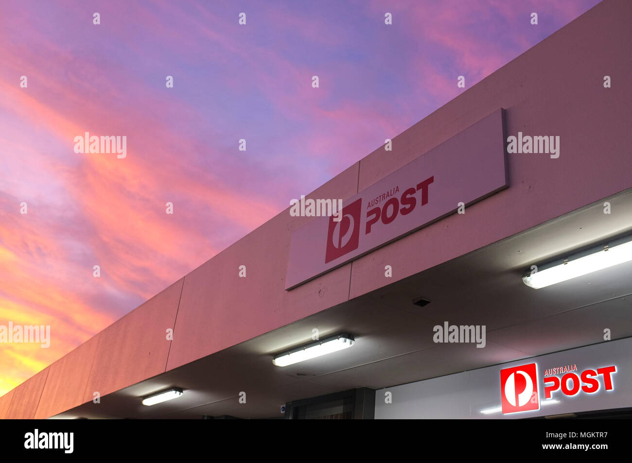 The Australia Post signs at the top of a shopfront at sunset in ...